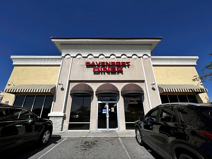The gleaming white exterior of Davenport Diner stands like a beacon of breakfast hope against the Florida sky, promising culinary comfort within those navy-awninged doors.