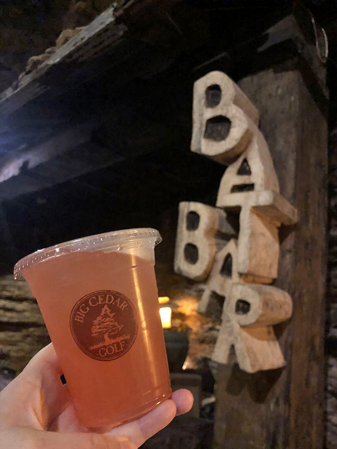 Big Cedar Golf's signature drink glows warmly against the natural cave backdrop and stone formations.
