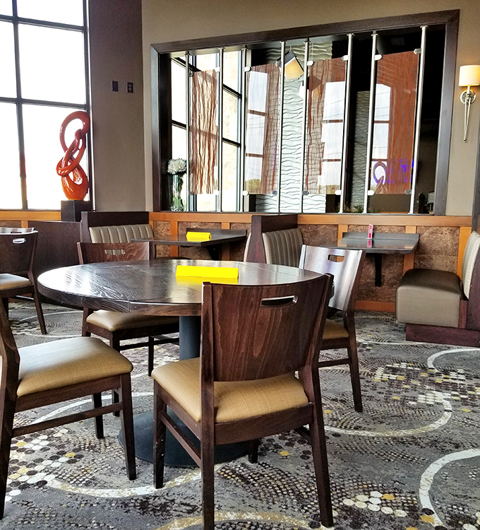 Elegant booth seating with artistic dividers creates intimate dining spaces where conversations flow as smoothly as the service.