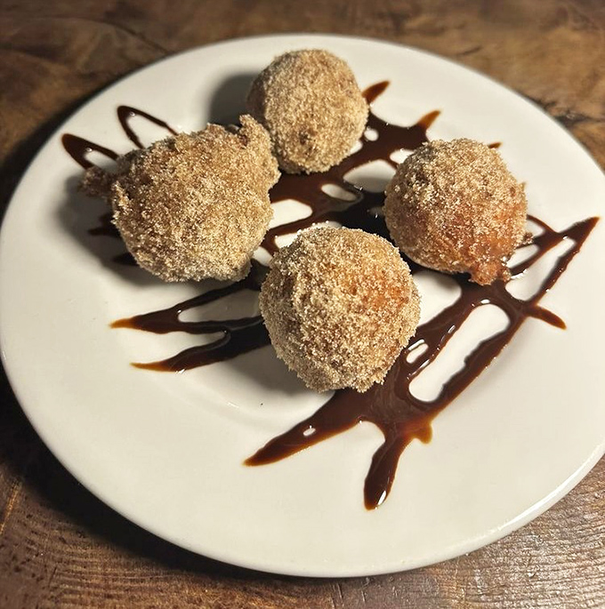 These golden, sugar-dusted zeppole aren't just dessert&mdash;they're warm little spheres of joy that make you forget you're in a historic saloon.
