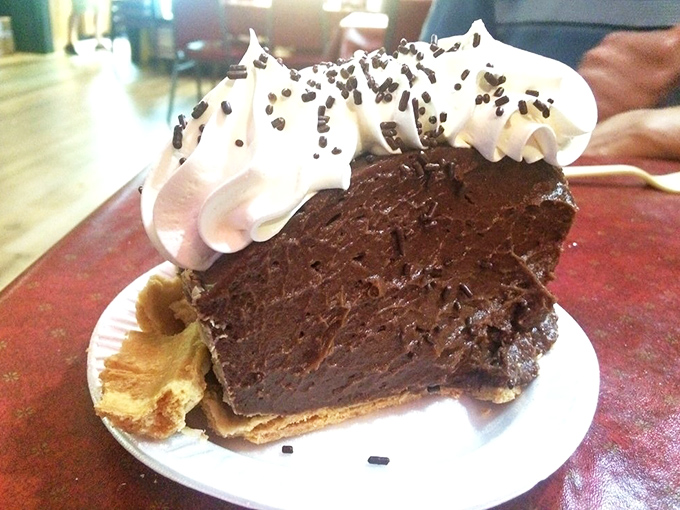 A slice of chocolate pie so rich and dense it should have its own tax bracket, crowned with a cloud of whipped cream.