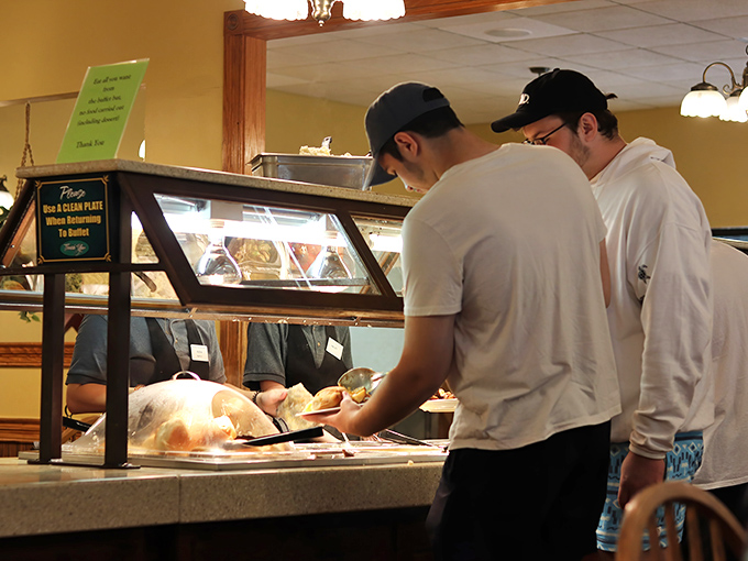 Young folks manning the buffet line with the focus of surgeons performing delicious operations.
