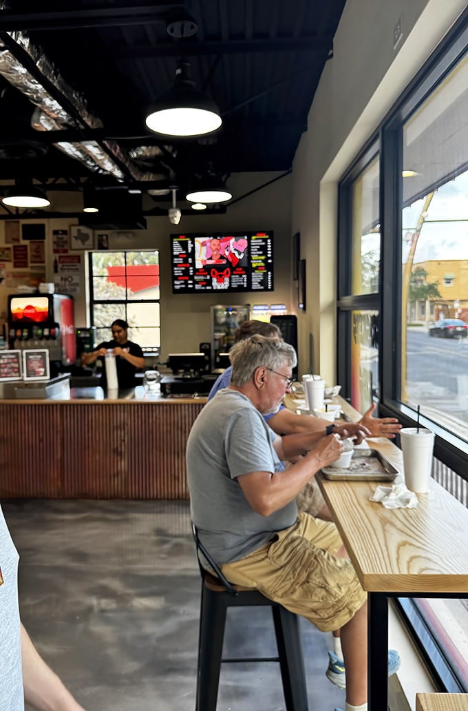Solo diners find solace at the window counter, watching the world while savoring exceptional barbecue.