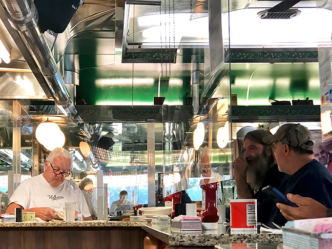 Where breakfast magic happens. The griddle maestros orchestrate your morning symphony while regulars provide the familiar background chatter.