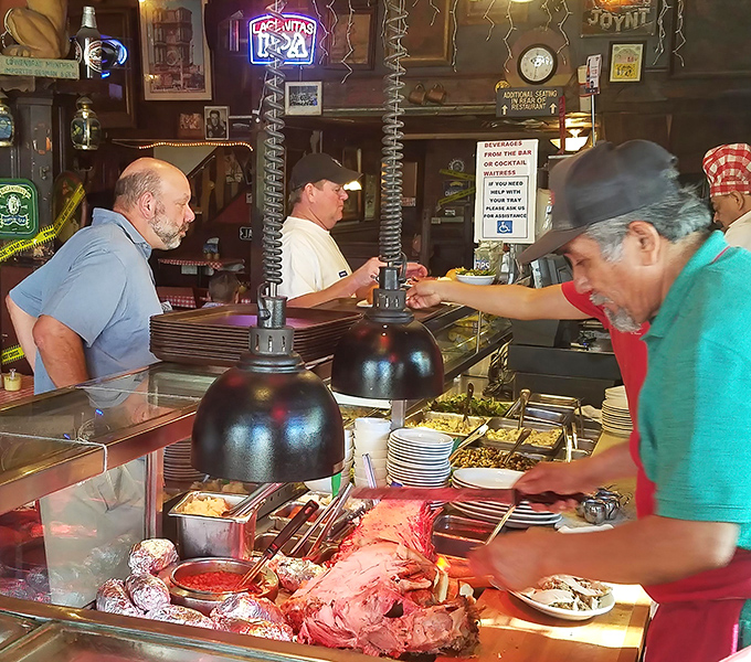 At the carving station, meat meets knife in a dance as old as time, while hungry patrons wait their turn with the patience of saints.
