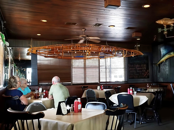 The wooden canoe suspended from the ceiling reminds diners of the connection between water, fishing, and the feast on their plates. 