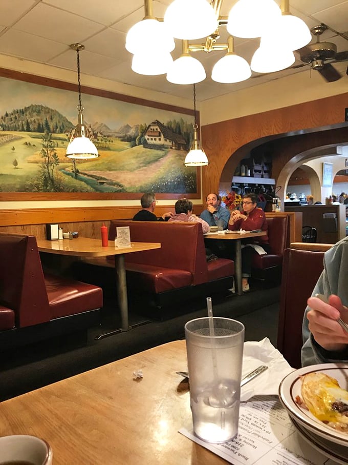 Under warm pendant lights, diners savor meals beneath a pastoral mural that feels like a window to another time and place.