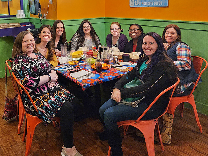 Friends gathered around colorful tablecloths, proving that breakfast shared is happiness multiplied&mdash;especially when biscuits are involved.