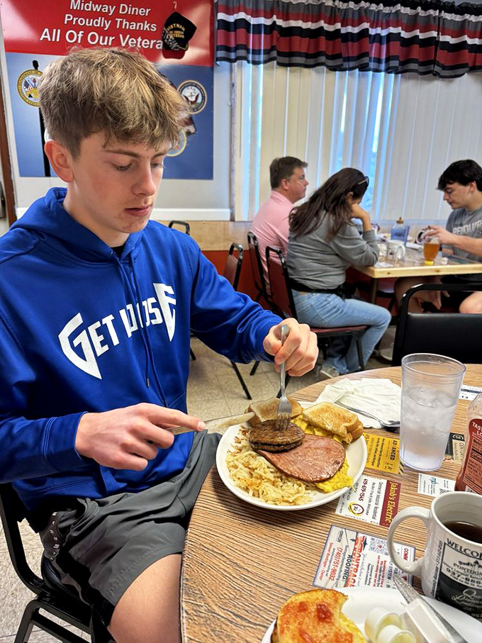 A sign thanking veterans hangs prominently as diners enjoy hearty plates—because at Midway, respect for community is served alongside every omelet and stack of pancakes.