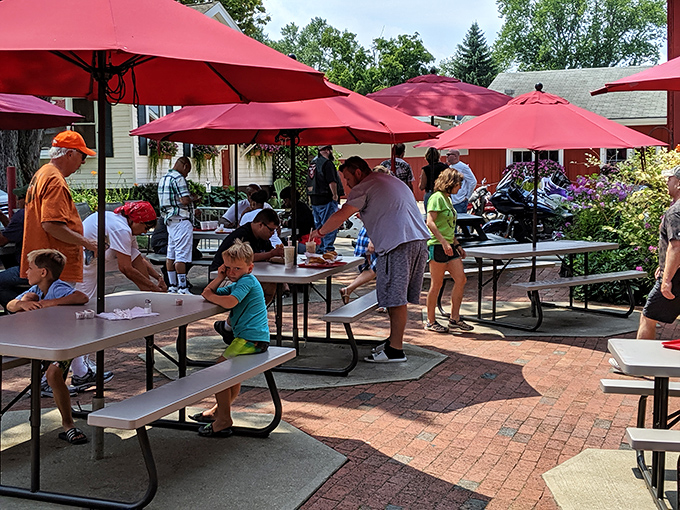 Under cheerful red umbrellas, strangers become neighbors and neighbors become friends. This patio isn't just outdoor seating—it's community building, one meal at a time.