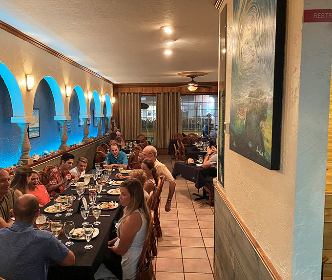 The blue-lit dining room transforms into a convivial gathering spot where strangers become friends, united by their mutual love of great seafood.