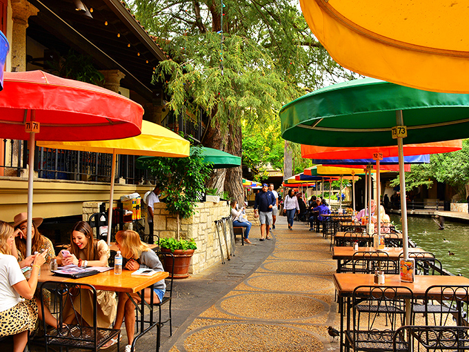 Those colorful umbrellas aren't just for show – they're beacons guiding hungry travelers to riverside tables where memories are served alongside margaritas.