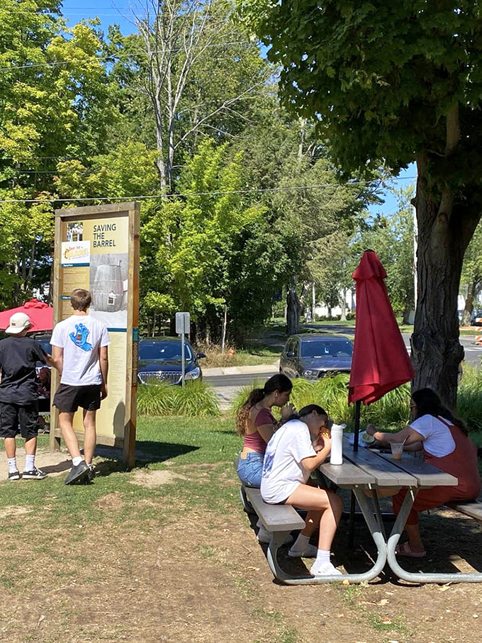 The "Saving the Barrel" sign tells a story of community preservation while visitors focus on preserving summer memories, one bite at a time.