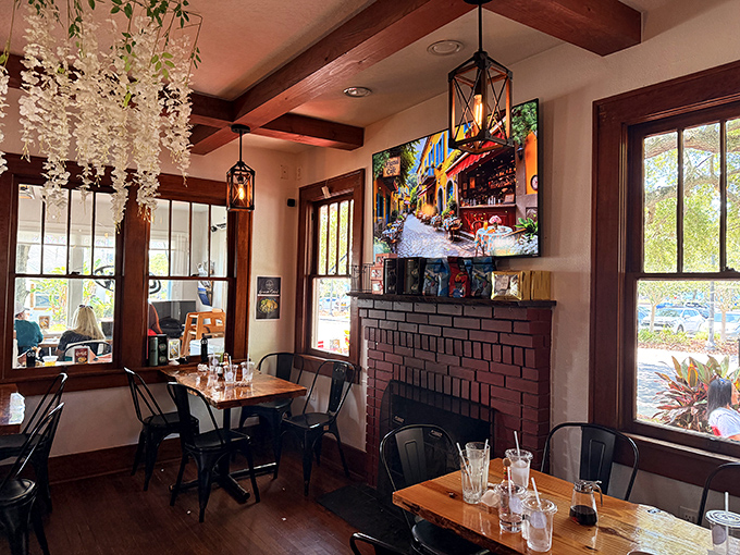 Exposed wooden beams, hanging lanterns, and large windows create a dining space where comfort meets charm, with a fireplace that adds unexpected coziness to Florida mornings.