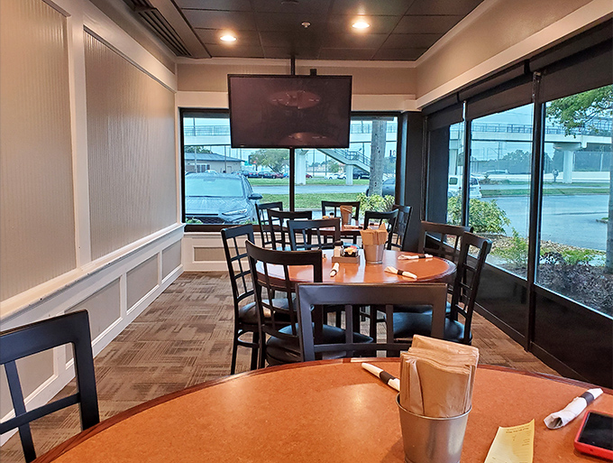 Sun streams through windows in this cozy corner, where wooden tables await families and the TV stands ready for Florida's inevitable afternoon thunderstorms.
