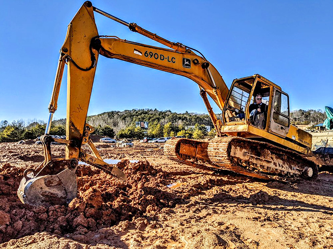 Construction equipment transforms ordinary visitors into temporary heavy machinery operators with infectious grins.