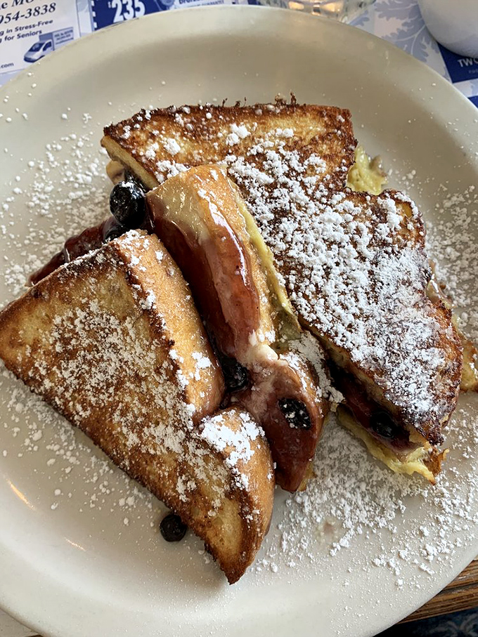 French toast that's crossed the line from breakfast to dessert, with powdered sugar and what appears to be blueberry filling in a delicious conspiracy.