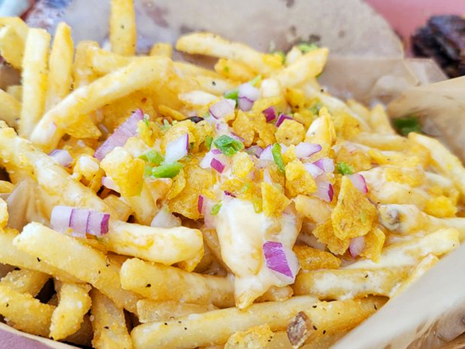 Fries transformed into a canvas of culinary creativity. Those crispy potatoes beneath queso, Fritos, and onions are having their best possible life.