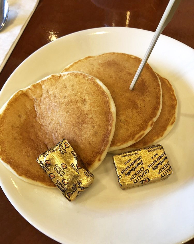 Three perfect pancakes with butter pats still in their gold wrappers&mdash;like breakfast presents waiting to be unwrapped and devoured.