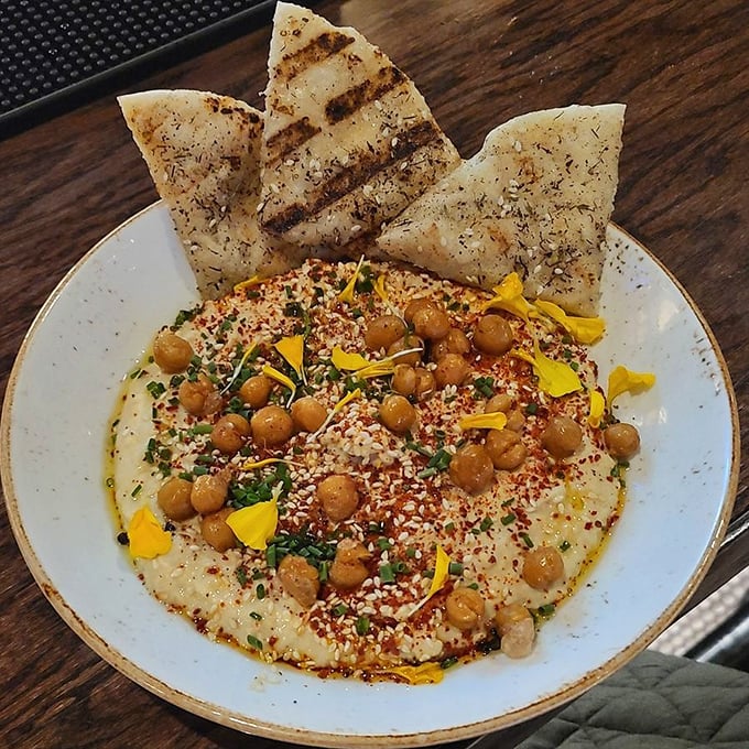 Hummus elevated from casual dip to centerpiece attraction. Crispy chickpeas and vibrant garnishes transform this Mediterranean staple into a conversation starter.