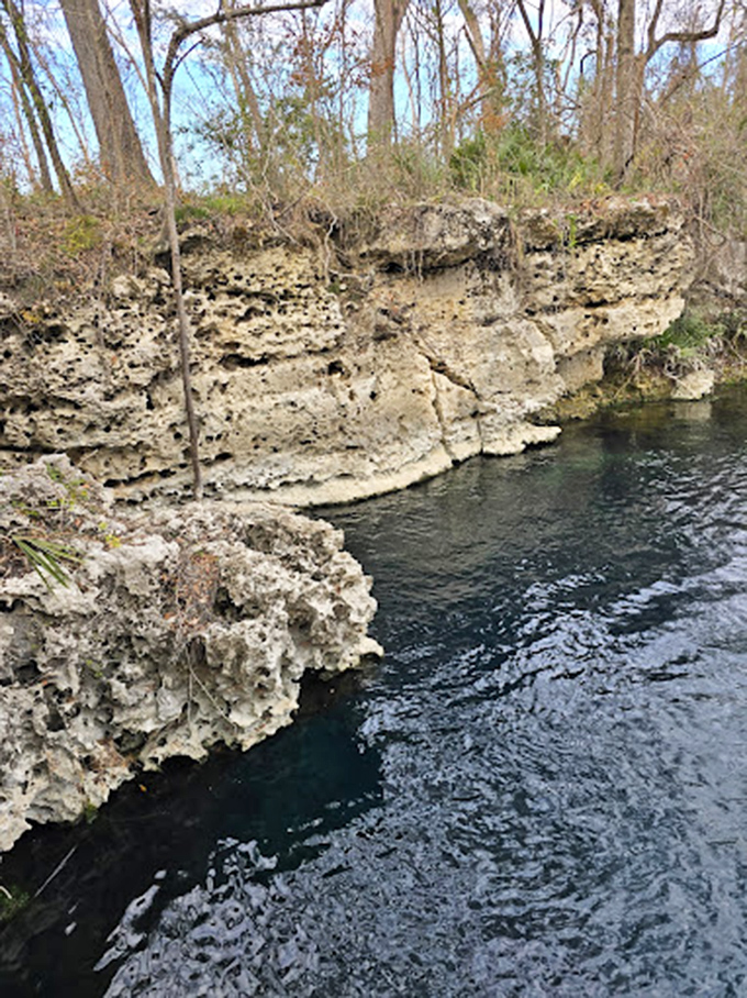 Ancient limestone cliffs standing guard over secrets hidden beneath the crystal-clear surface.