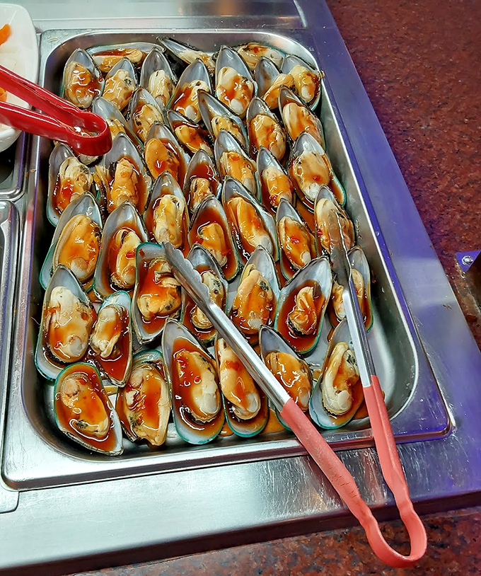 Mussels lined up like soldiers in a delicious sauce battalion. The red tongs stand ready for your next move.