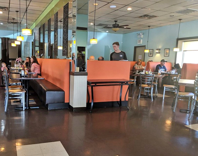 Another angle reveals more coral booths and wooden tables where breakfast dreams come true one hollandaise-covered bite at a time.