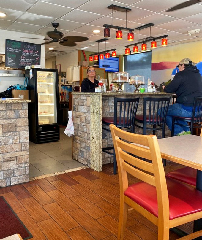 Red pendant lights cast a warm glow over the stone-accented counter, creating that "everybody knows your name" vibe missing from chain restaurants.
