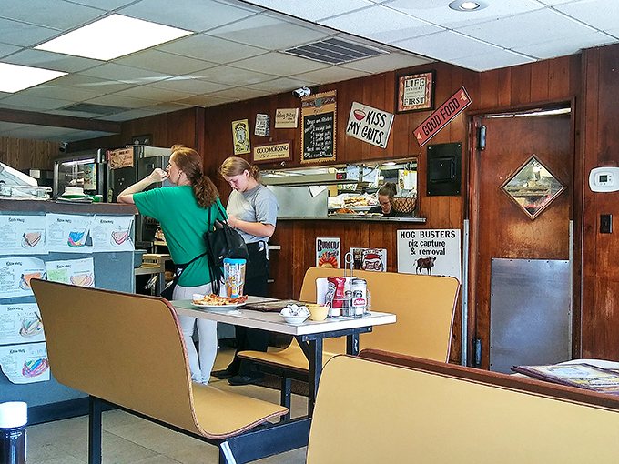 The kitchen pass-through where magic happens. Those "Kiss My Grits" signs aren't just decoration &ndash; they're a philosophy.