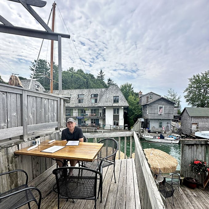 A solo diner enjoys the ultimate waterfront table, where boats drift by close enough to ask if they'd share their fries.