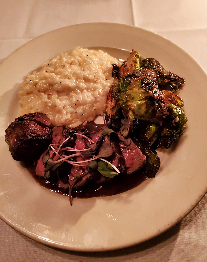 Pan-seared elk loin showcases culinary adventure alongside creamy risotto and perfectly roasted Brussels sprouts.