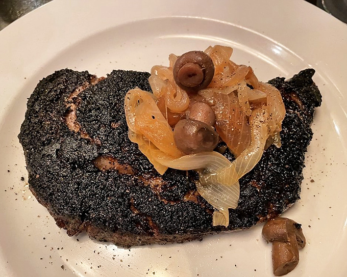This blackened steak with caramelized onions and mushrooms isn't just cooked &ndash; it's been transformed through fire and skill into something transcendent.
