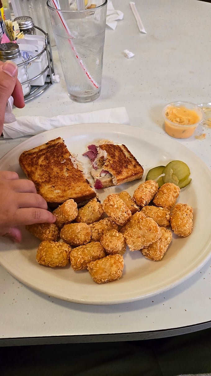 Half-eaten Reuben with tater tots&mdash;the only tragedy here is that someone had the willpower to stop eating this masterpiece midway.