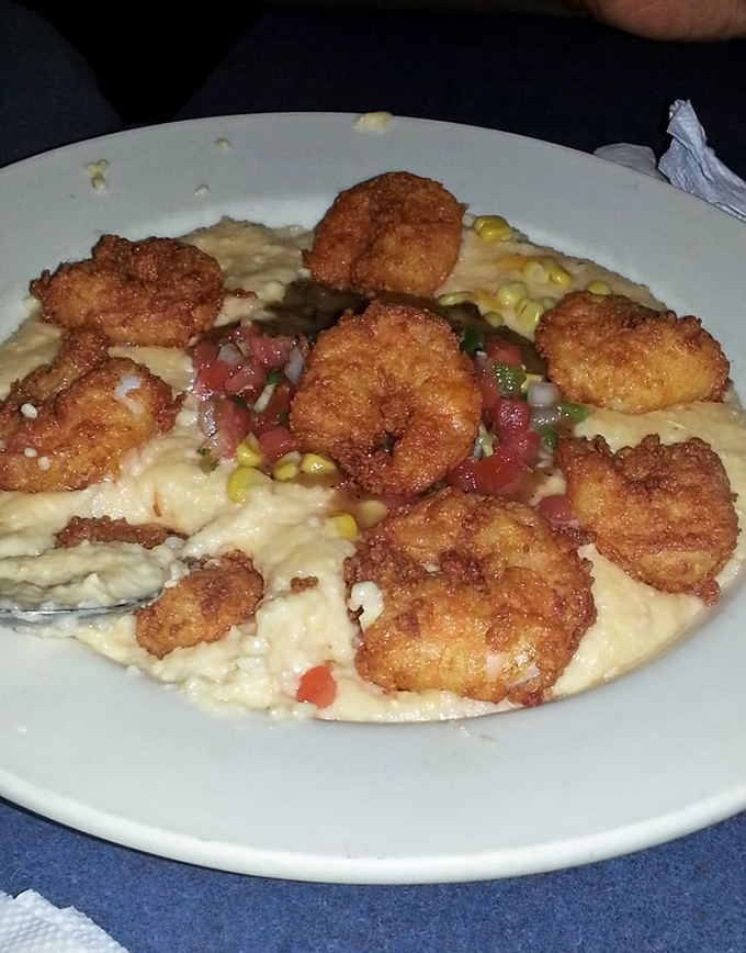Shrimp and grits elevated to an art form—plump crustaceans nestled on a bed of creamy corn goodness, with fresh vegetables adding color and zing.
