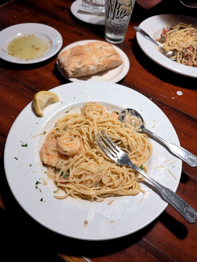 Shrimp scampi pasta that twirls perfectly around your fork. The bread and dipping oil in the background are plotting to steal your attention.