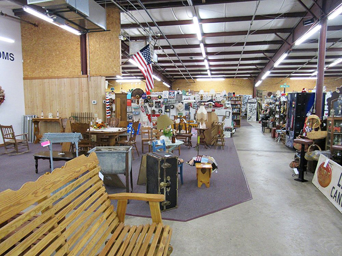 The American flag stands sentinel over this section, where wooden benches invite weary shoppers to rest while contemplating whether they really need that vintage suitcase.