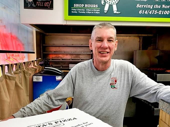 The smile of someone who knows he's making memories, not just meals. This is the face of pizza passion.