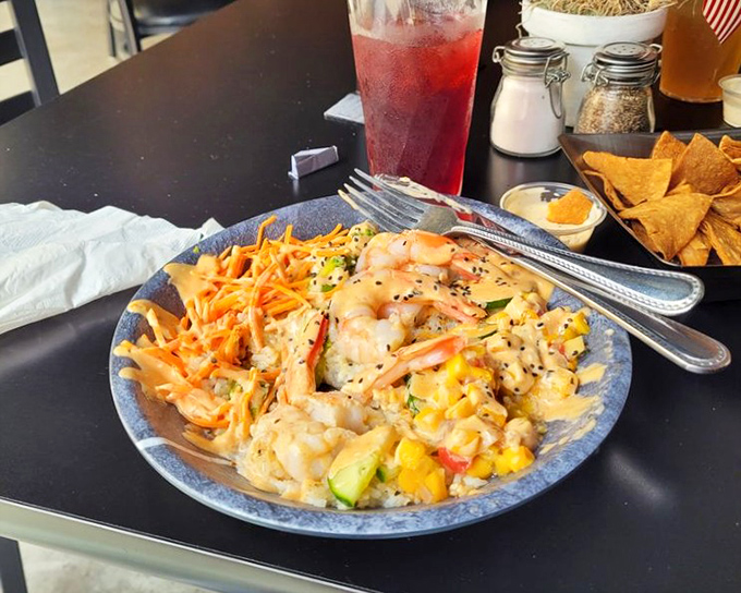 A colorful seafood bowl that's both feast and art. Vibrant vegetables, succulent shrimp, and what appears to be mango create a tropical vacation on a plate.