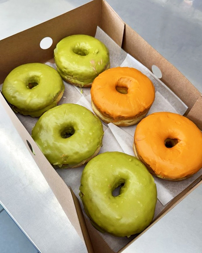 These vibrant green and orange donuts aren't having an identity crisis&mdash;they're boldly showcasing Thai tea flavors in donut form. Cultural fusion at its finest.