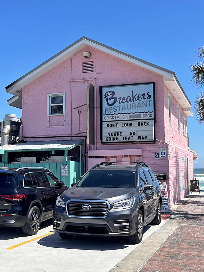 The Breakers' iconic pink facade has witnessed countless sunrises and beach days. Their humorous sign reminds us that ocean views are always the right direction.