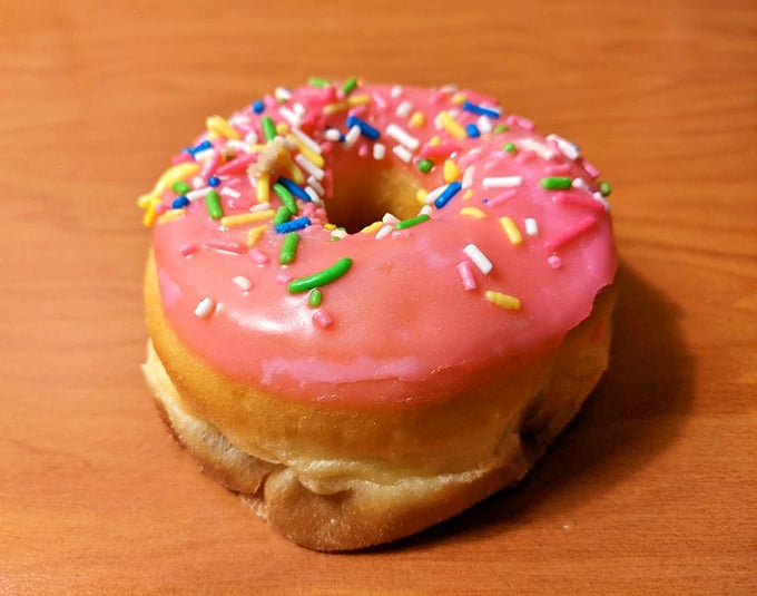 A single pink-frosted donut with rainbow sprinkles&mdash;the kind that makes grown adults smile like they're eight years old again. Simple joy, perfectly executed.