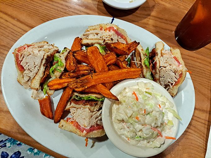 The turkey club sandwich: architectural marvel meets culinary genius, served with sweet potato fries that steal hearts.