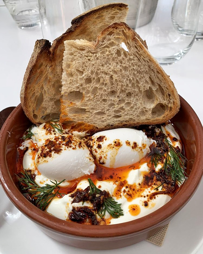 Turkish eggs&mdash;where yogurt meets poached eggs in a terra cotta hot tub of chili oil. Bread stands by for necessary dipping operations.
