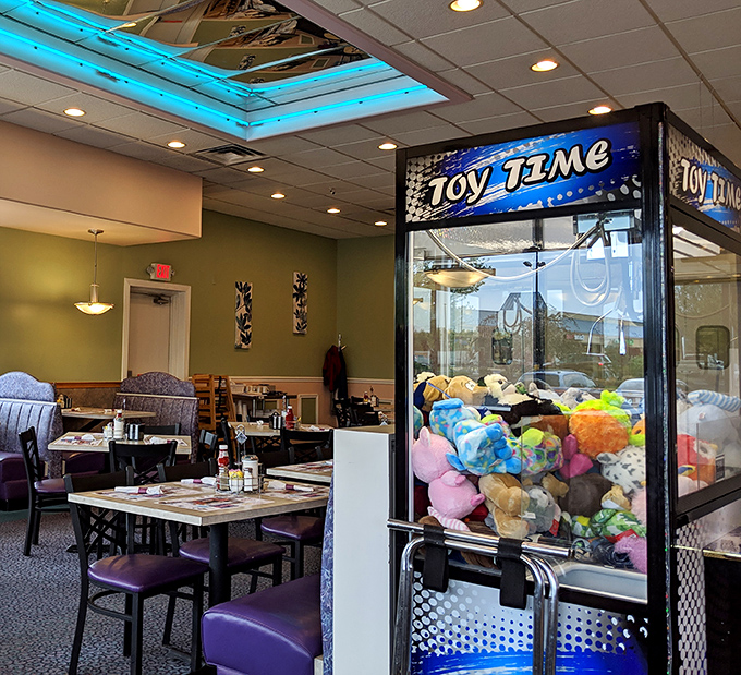 The claw machine stands guard near cozy booths, promising stuffed treasures to lucky winners and second chances to determined losers.