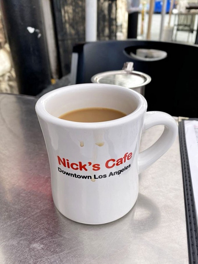 That sturdy white mug emblazoned with "Nick's Cafe" isn't just holding coffee; it's holding liquid motivation to face the day ahead.