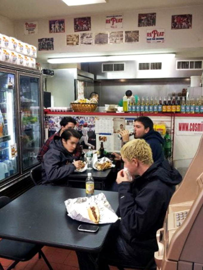 The universal language of sandwich appreciation brings people together at simple tables for moments of shared culinary bliss.