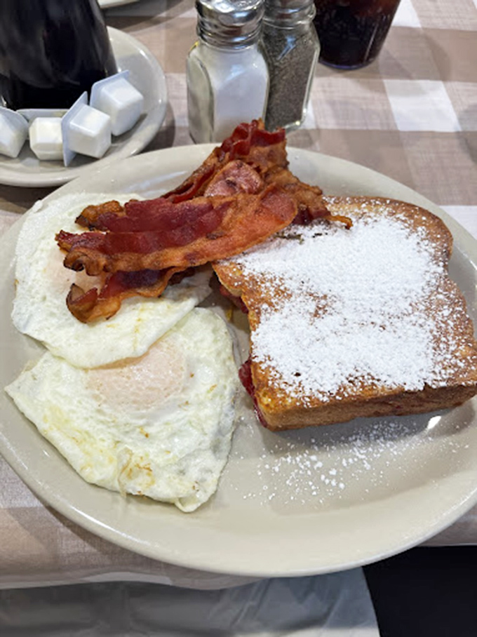 Breakfast that understands the importance of proper architecture: eggs, bacon, and French toast forming the holy trinity of morning perfection.