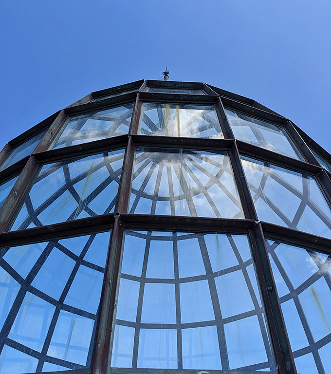 The lighthouse's glass dome catches sunlight like a giant jewel, its intricate ironwork frame creating patterns that dance across the interior walls.