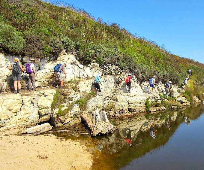 Hikers navigating Wilder Ranch's rocky shoreline. One wrong step and you're starring in your own personal blooper reel.