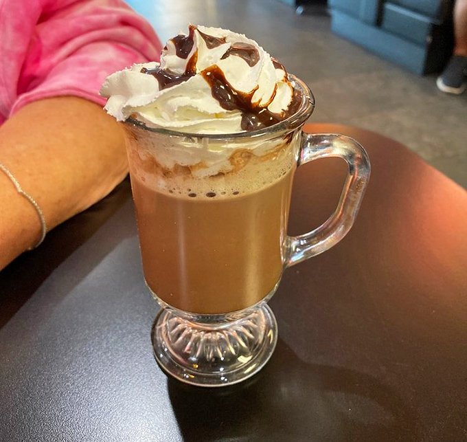 Hot chocolate elevated to an art form. That mountain of whipped cream topped with chocolate drizzle isn't just a beverage—it's dessert in a mug.